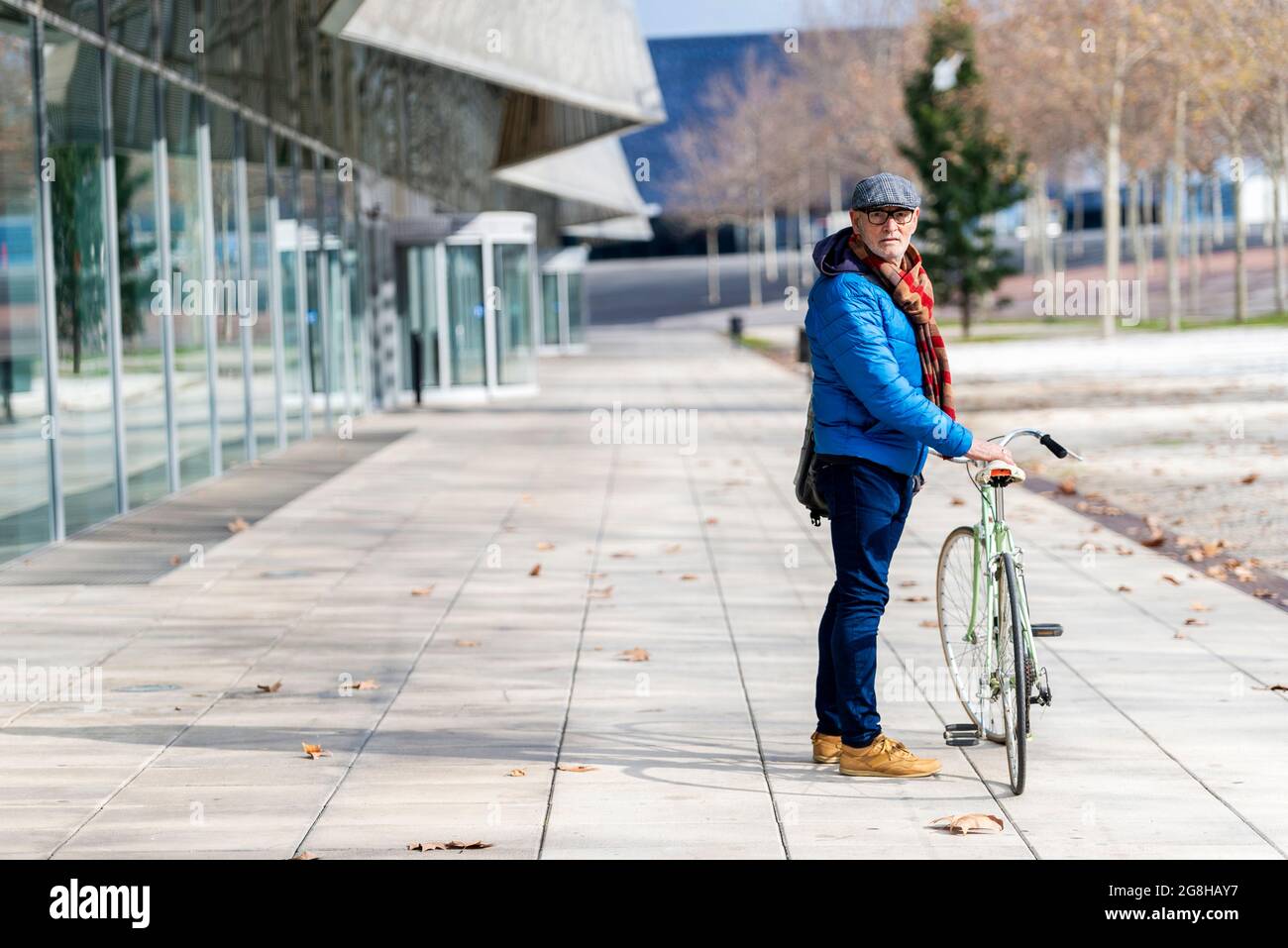 Senior man wheeling bicycle on city street holding a handbag Stock ...