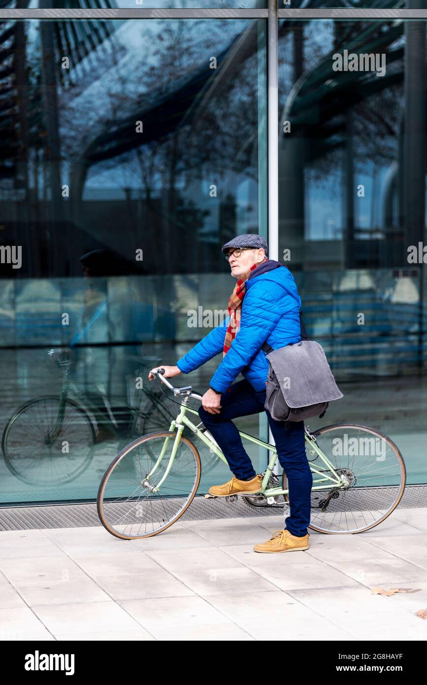 Senior man wheeling bicycle on city street holding a handbag Stock ...
