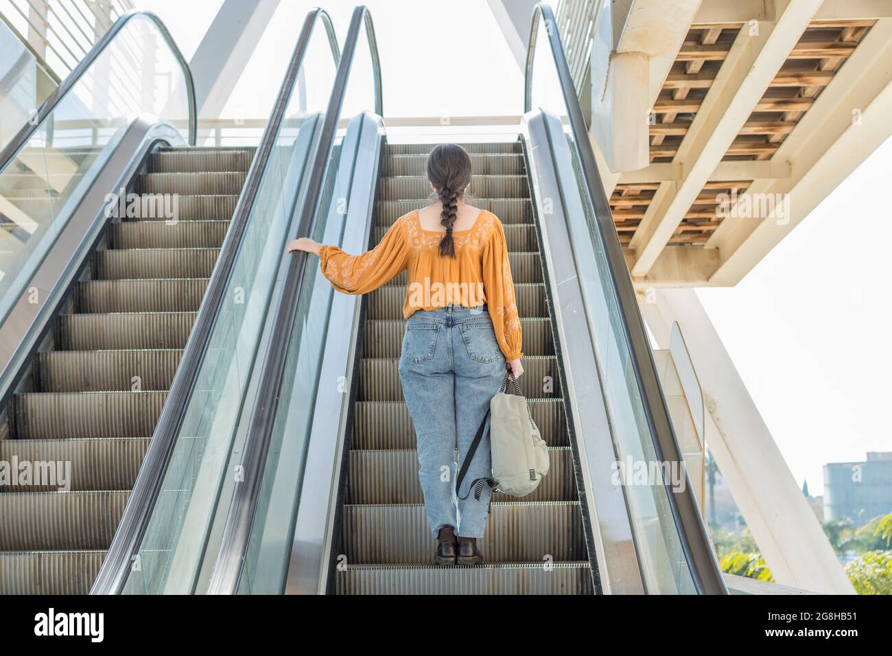 Full view of a young woman climbing an escalator Stock Photo - Alamy