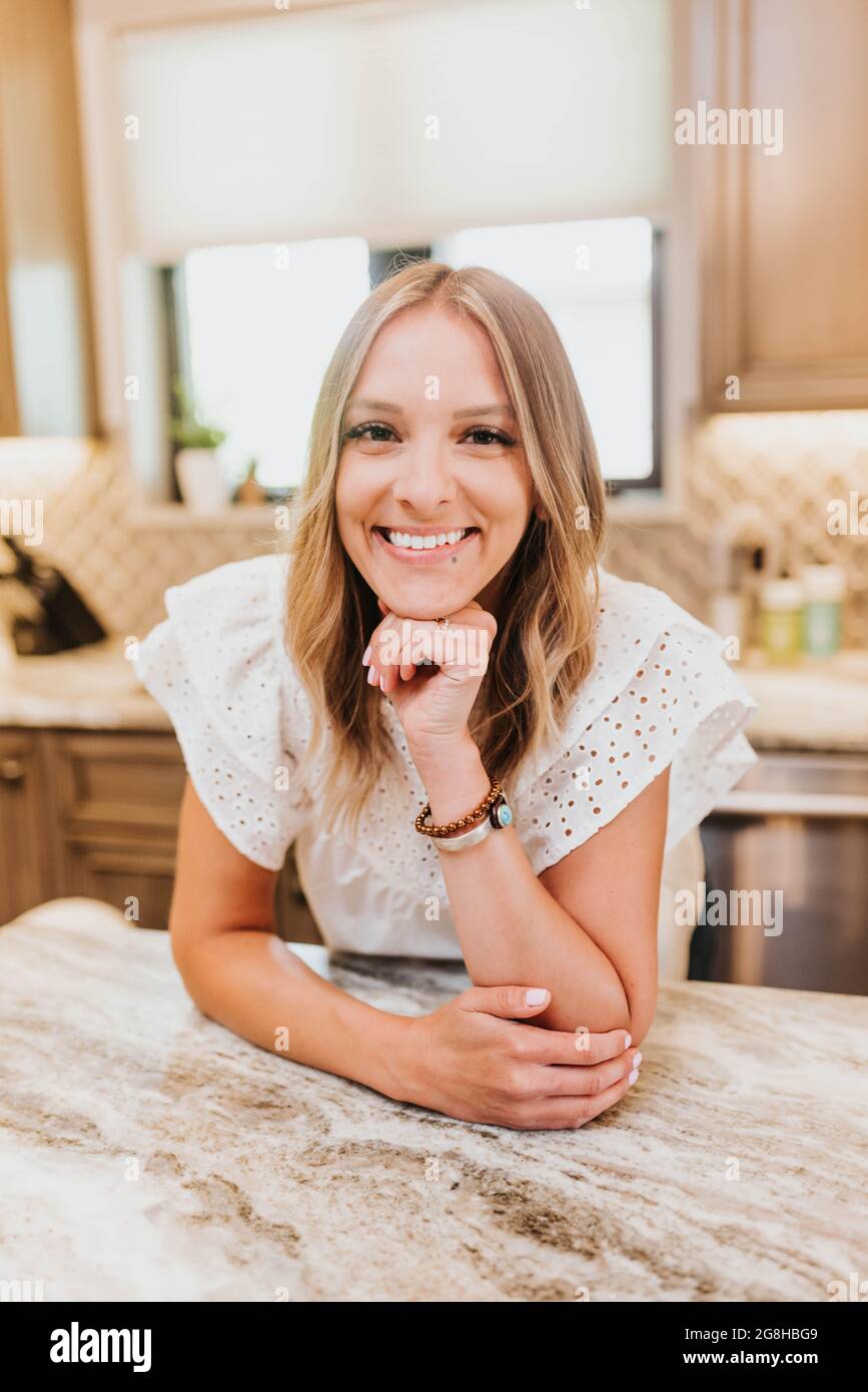 Woman leans on counter while looking at camera in her kitchen Stock ...