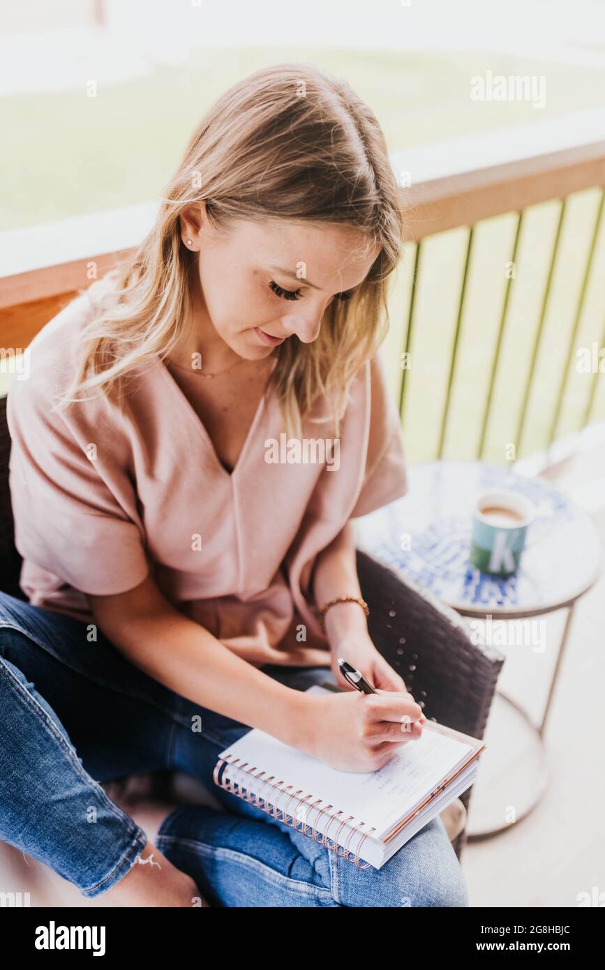 Woman writes in notebook outside on her porch Stock Photo - Alamy