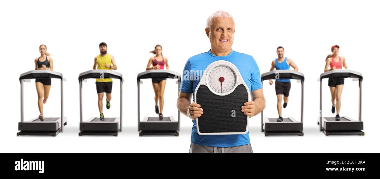 Mature man showing a weight scale in front of people running on ...
