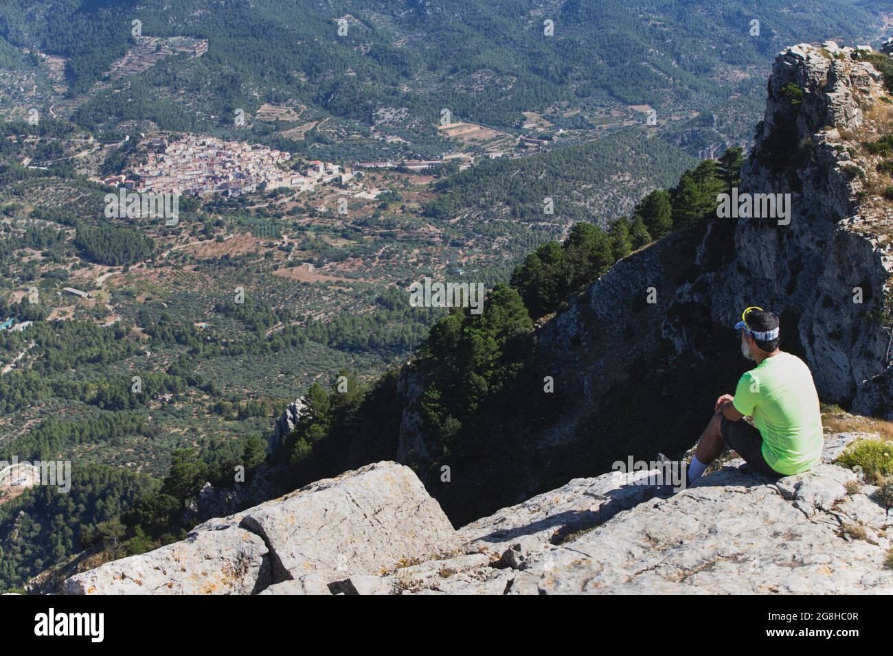 Side view of man sitting on cliff looking at mountains Stock Photo - Alamy