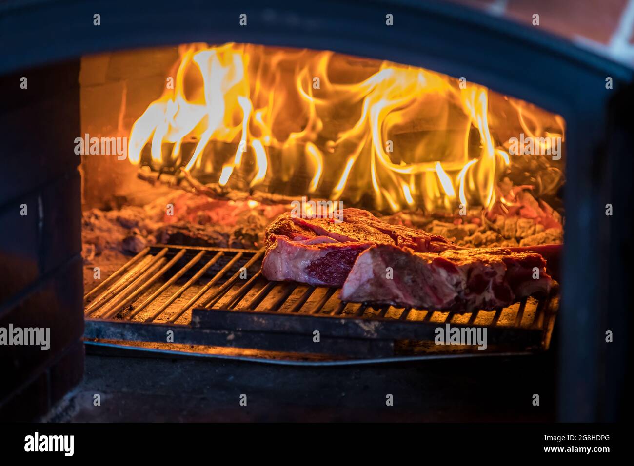 A traditional oven with a burning fire inside for cooking. Inside, raw ...