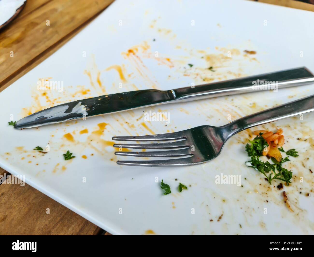 Used empty white plate with fork and knife Stock Photo - Alamy