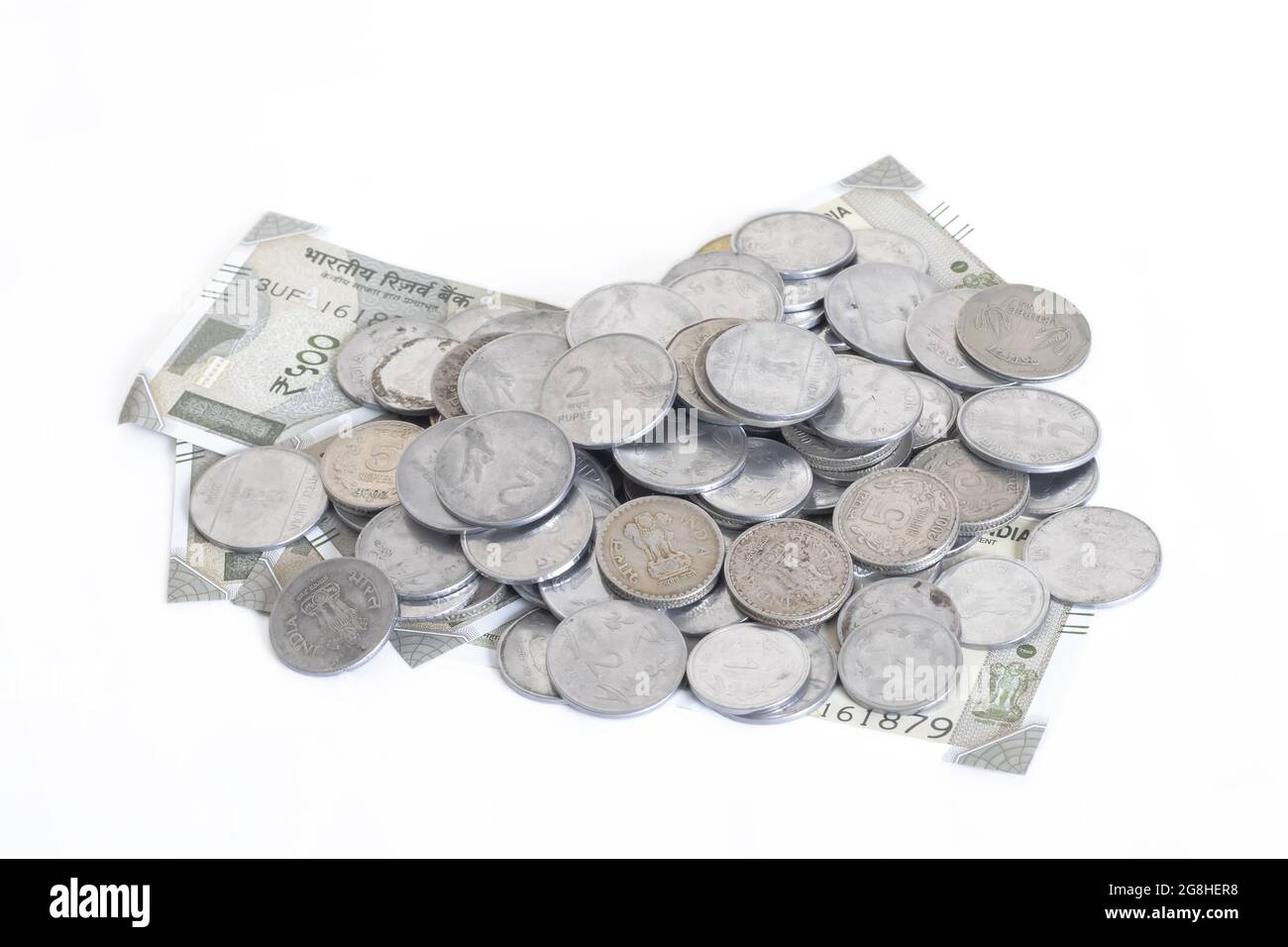 Pile of Indian rupee coins with bills beneath them on a white isolated ...