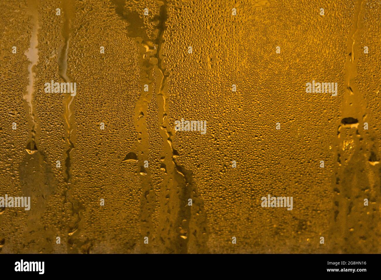 texture of fogged wet glass window in a room with warm light. vertical ...