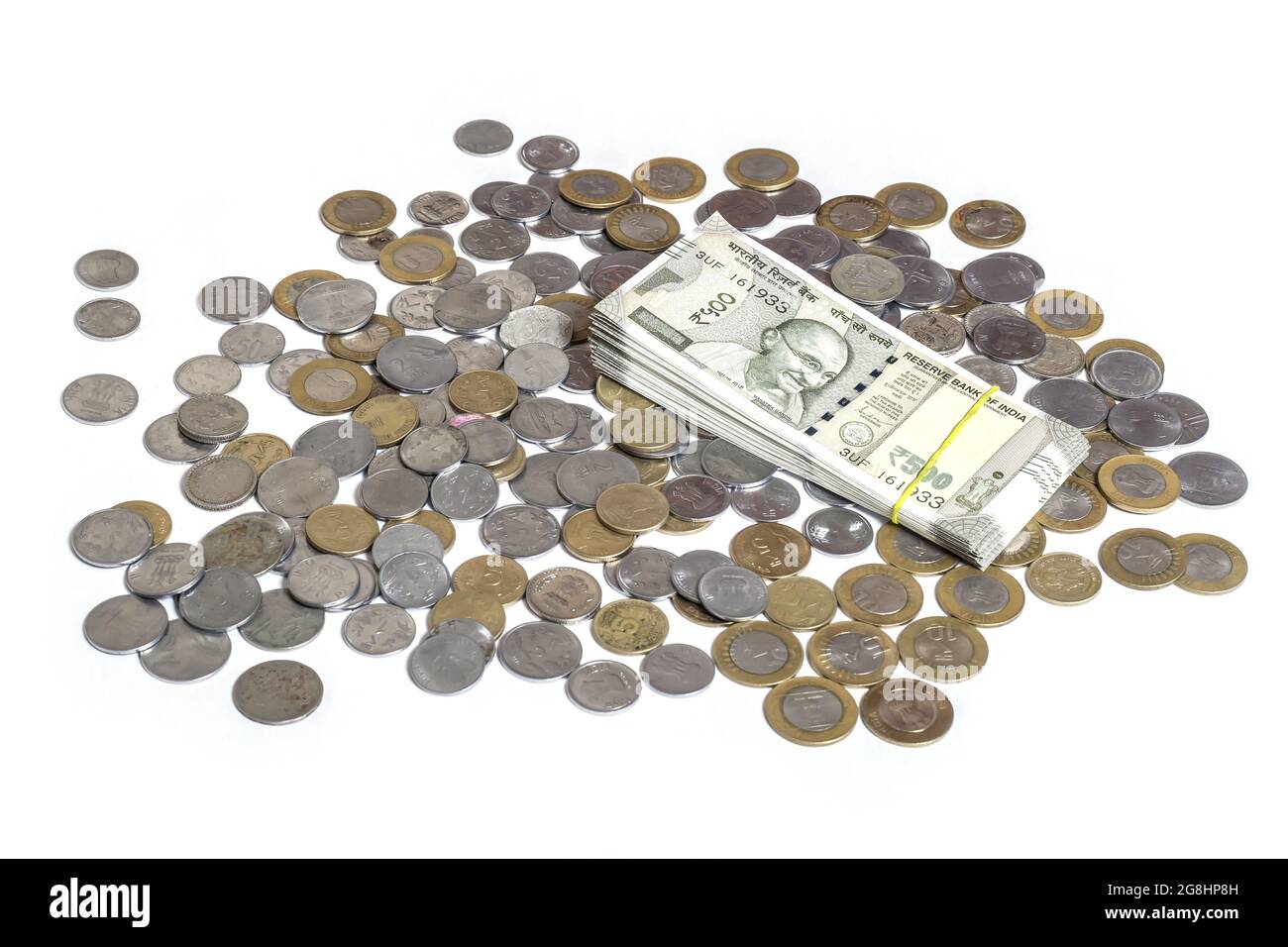 Stack of Indian rupee bills with coins scattered on an isolated white ...