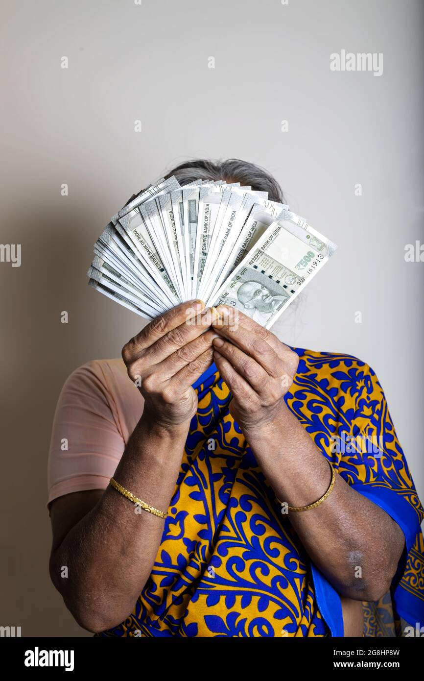 Indian lady with colorful traditional robes holding a stash of rupees ...