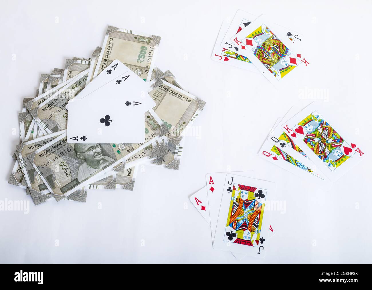 Pile of Indian rupee bills with poker cards scattered around on a plain ...