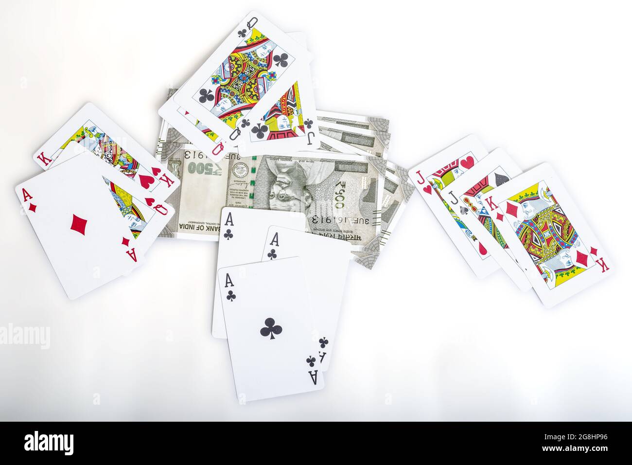 Top view of playing cards scattered around a pile of Indian rupee coins ...