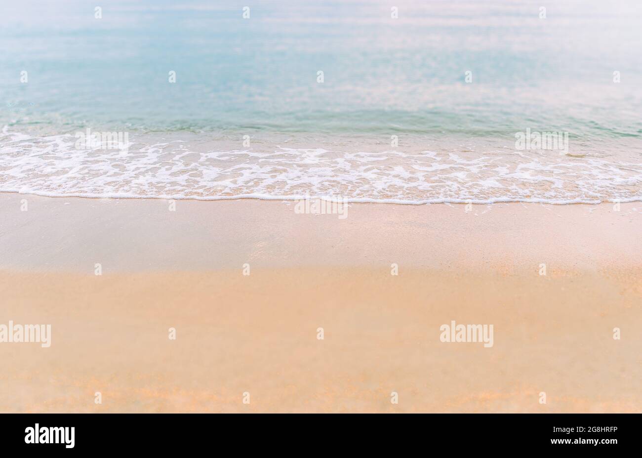 Small wave with the little white bubbles on a golden beach in sunset ...