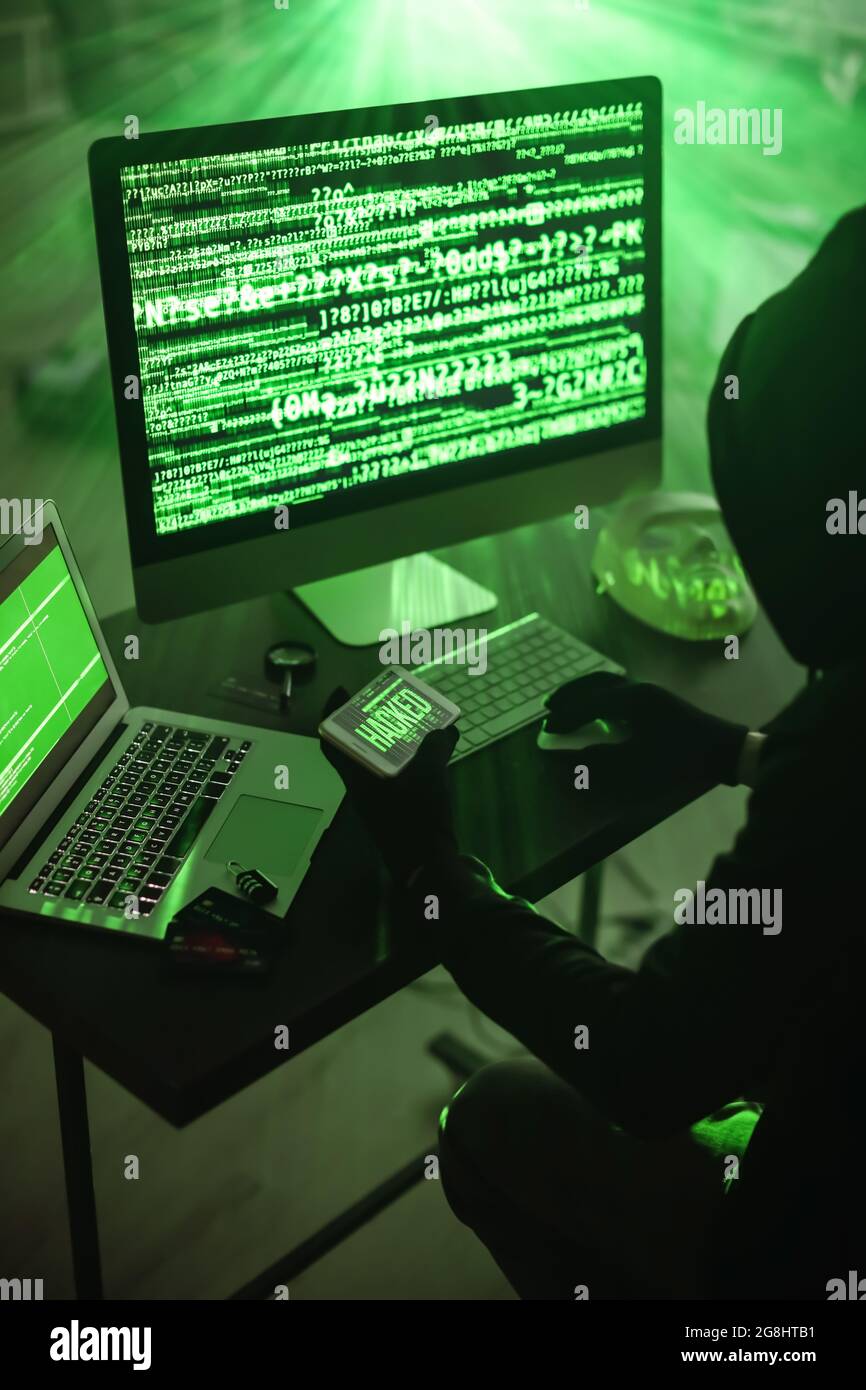 Hacker using computers in dark room Stock Photo - Alamy