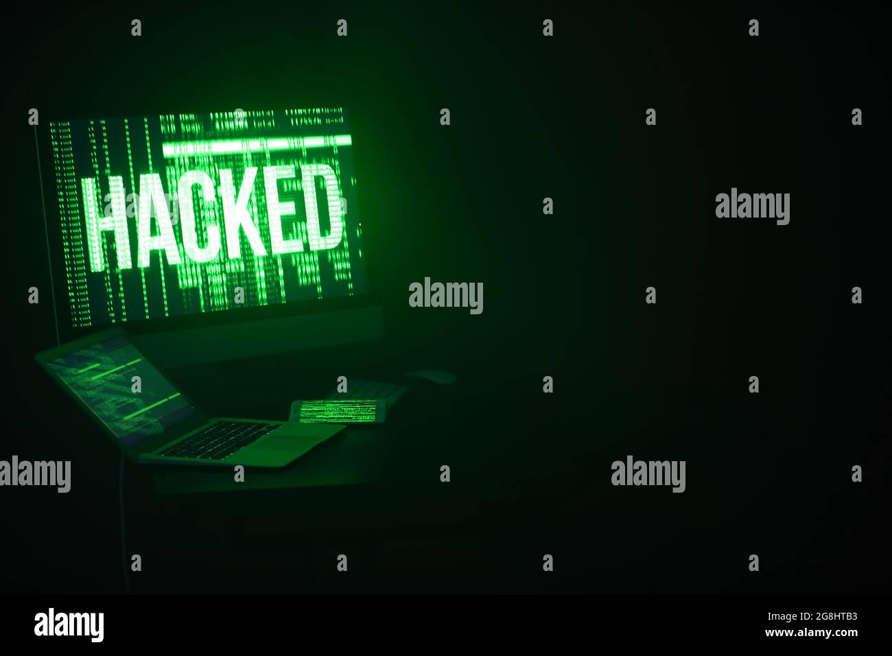 Computer with laptop and mobile phone at workplace of hacker in dark ...