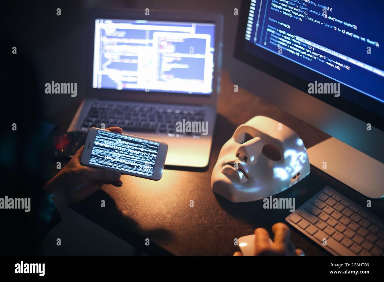 Hacker with mobile phone using computers in dark room Stock Photo - Alamy