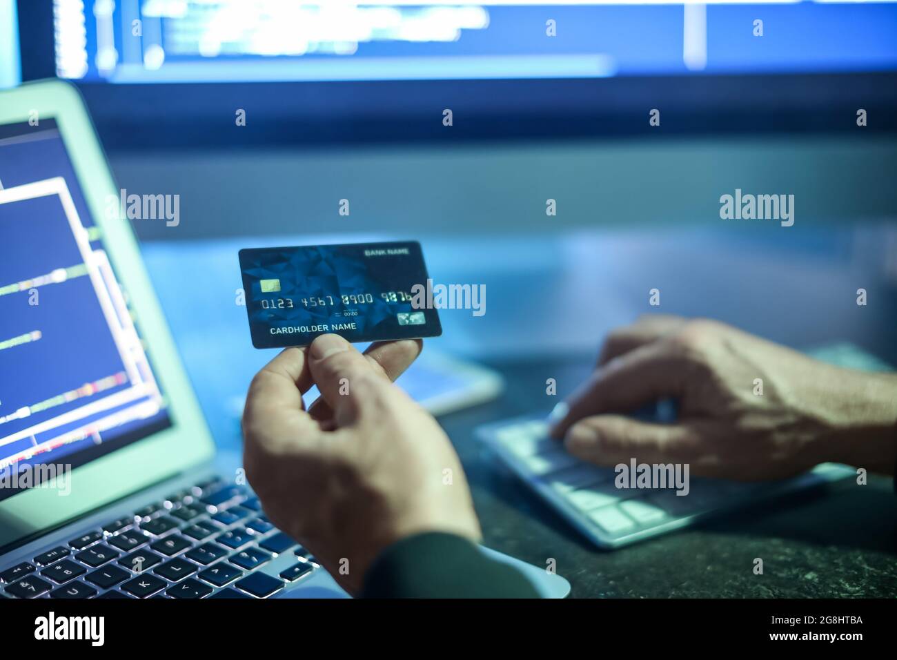 Hacker with credit card using computers in dark room Stock Photo - Alamy
