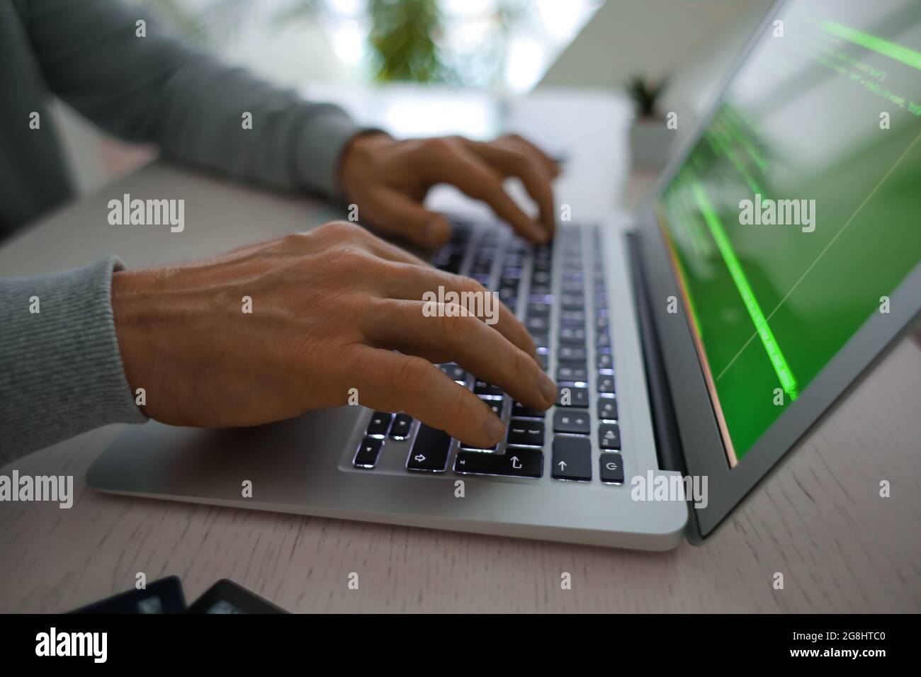 Hacker using computer at table Stock Photo - Alamy