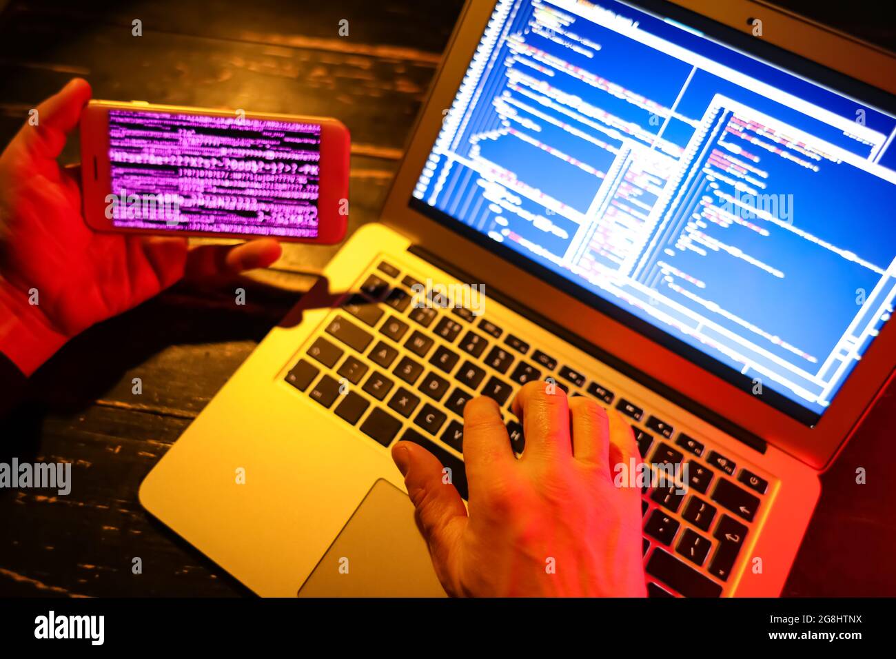 Hands of hacker with mobile phone and laptop on dark background Stock ...