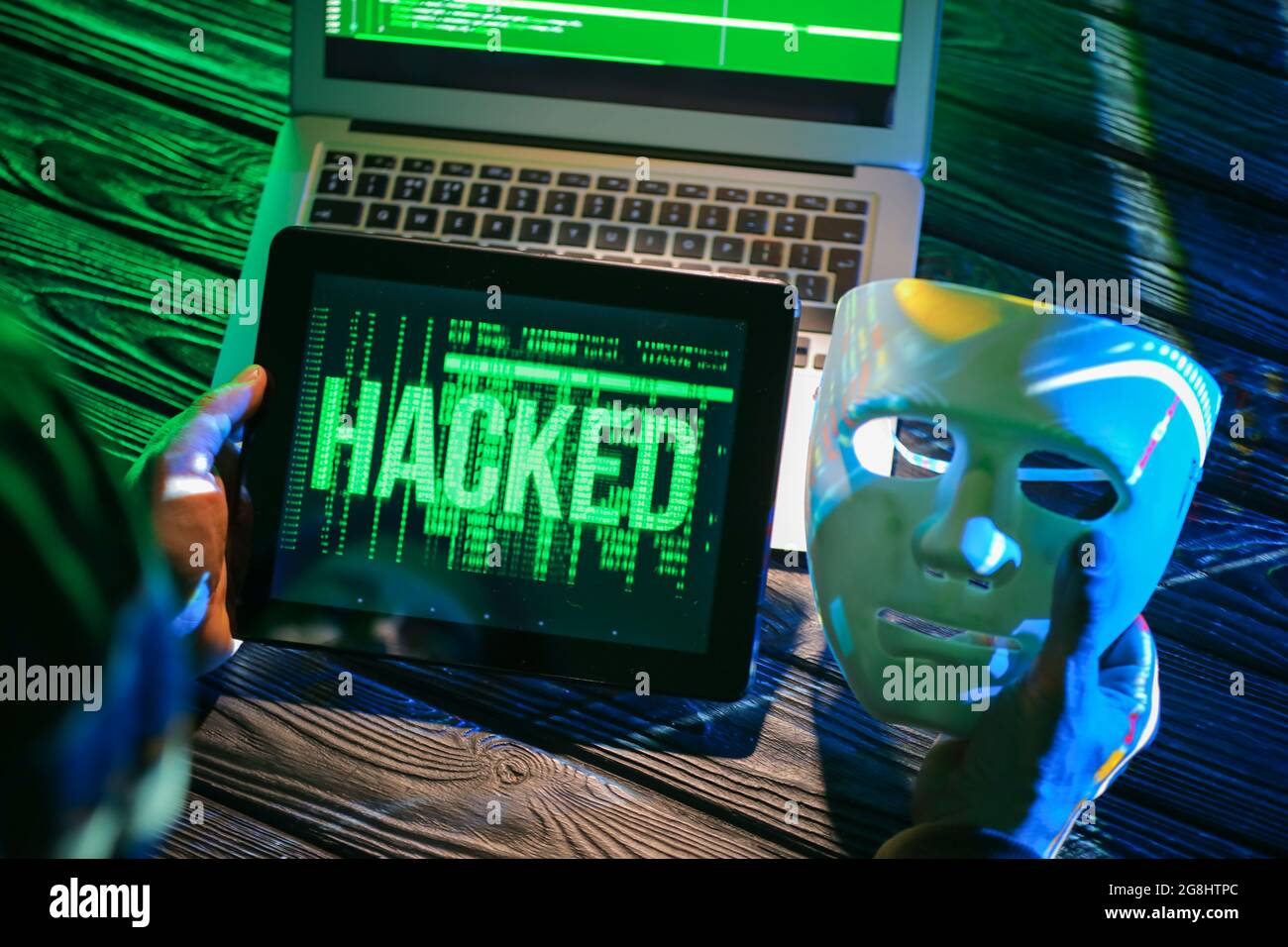 Hacker with mask using computer in dark room Stock Photo - Alamy