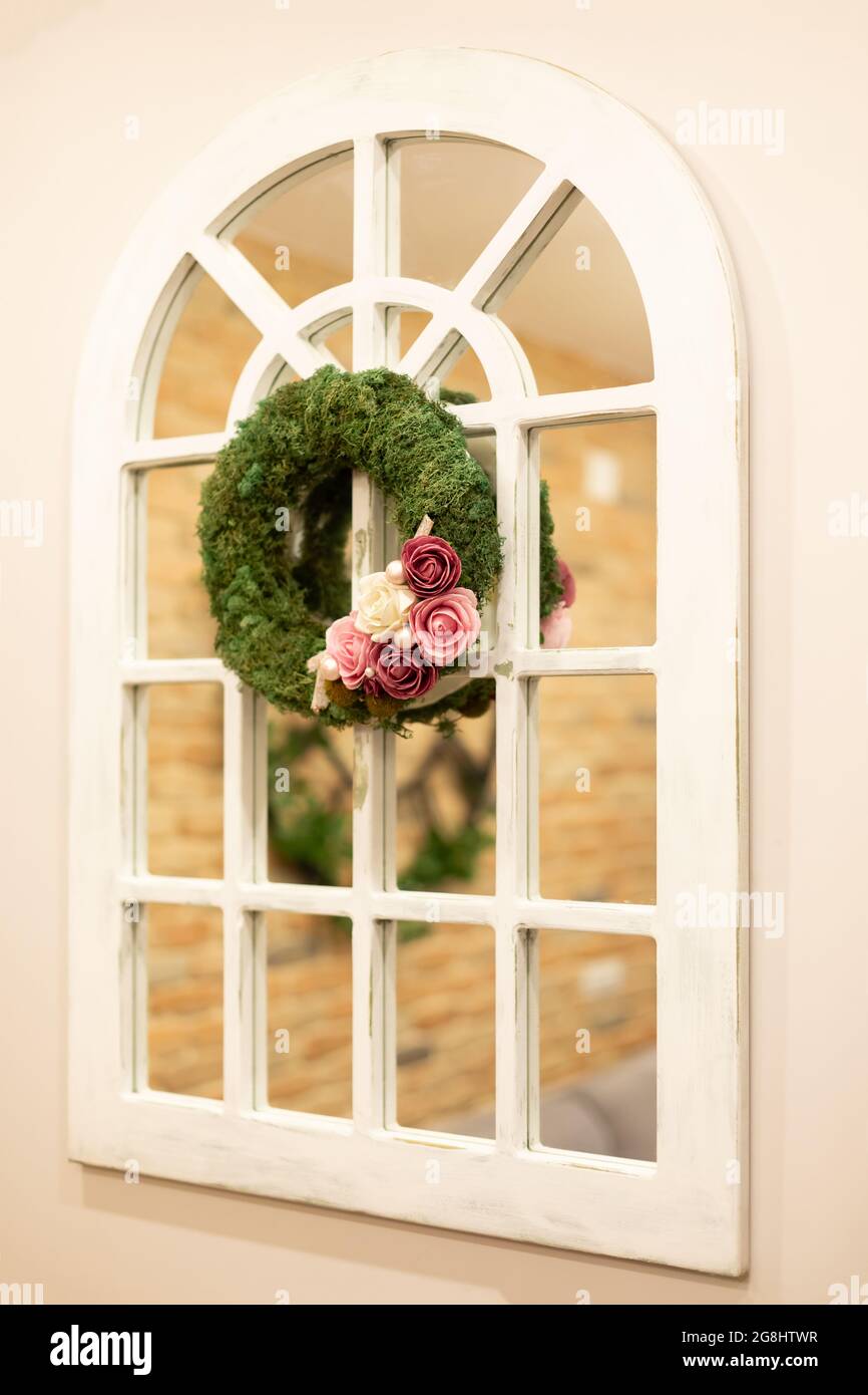 Decorative floral spring wreath hanging from a wooden arched windowpane ...