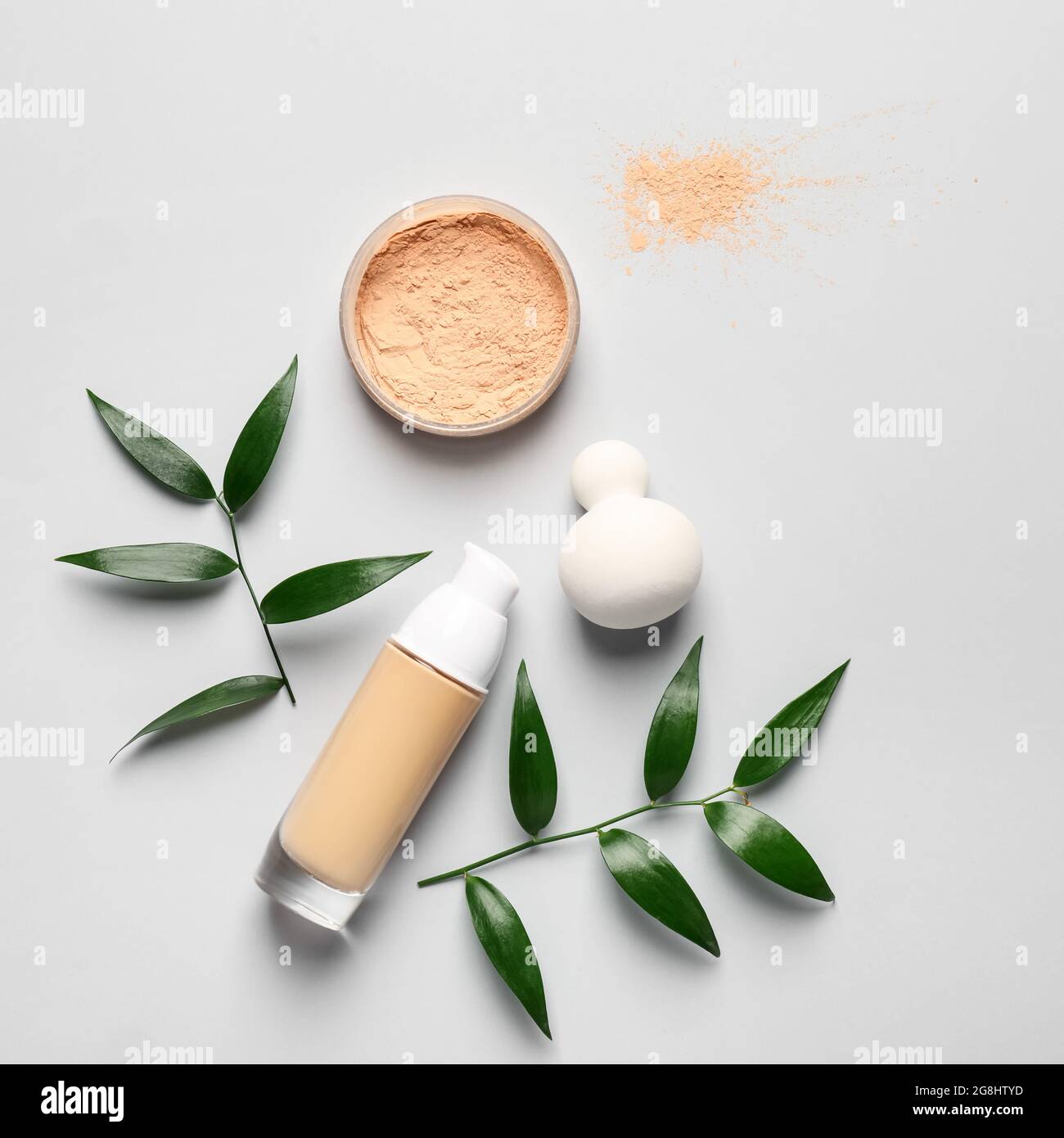 Makeup sponge with tonal foundation and powder on light background ...