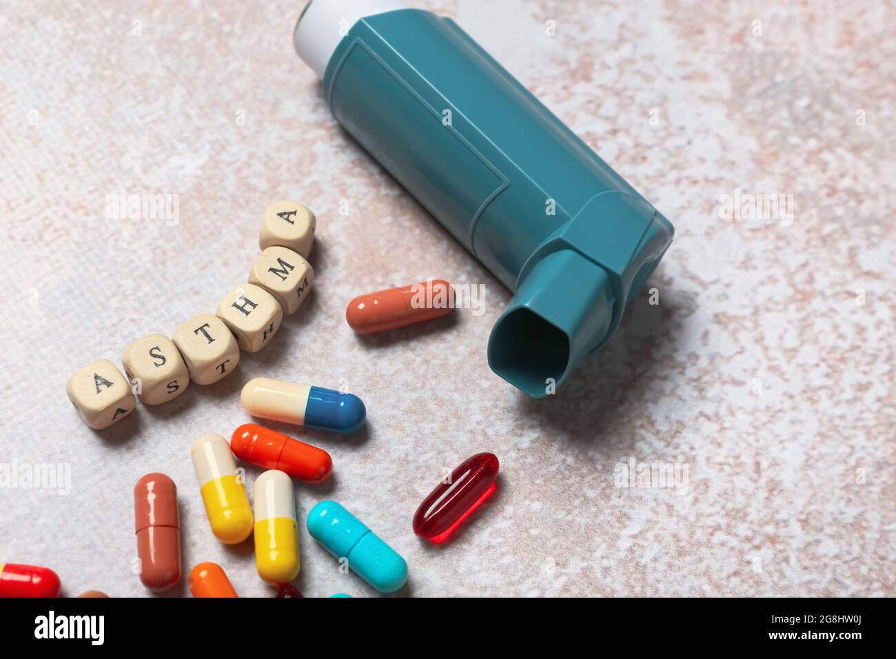 Modern inhaler, pills and word ASTHMA on grunge background, closeup ...