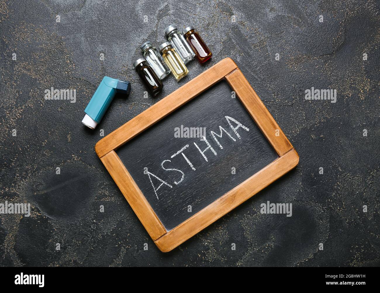 Modern inhaler, ampules and chalkboard with word ASTHMA on dark ...