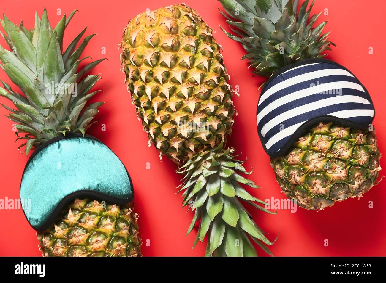 Fresh pineapples in sleeping masks on color background Stock Photo - Alamy