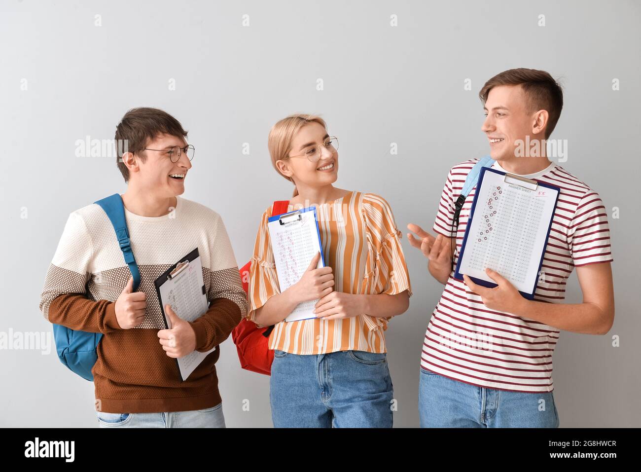 Students with answer sheets for school test on grey background Stock ...