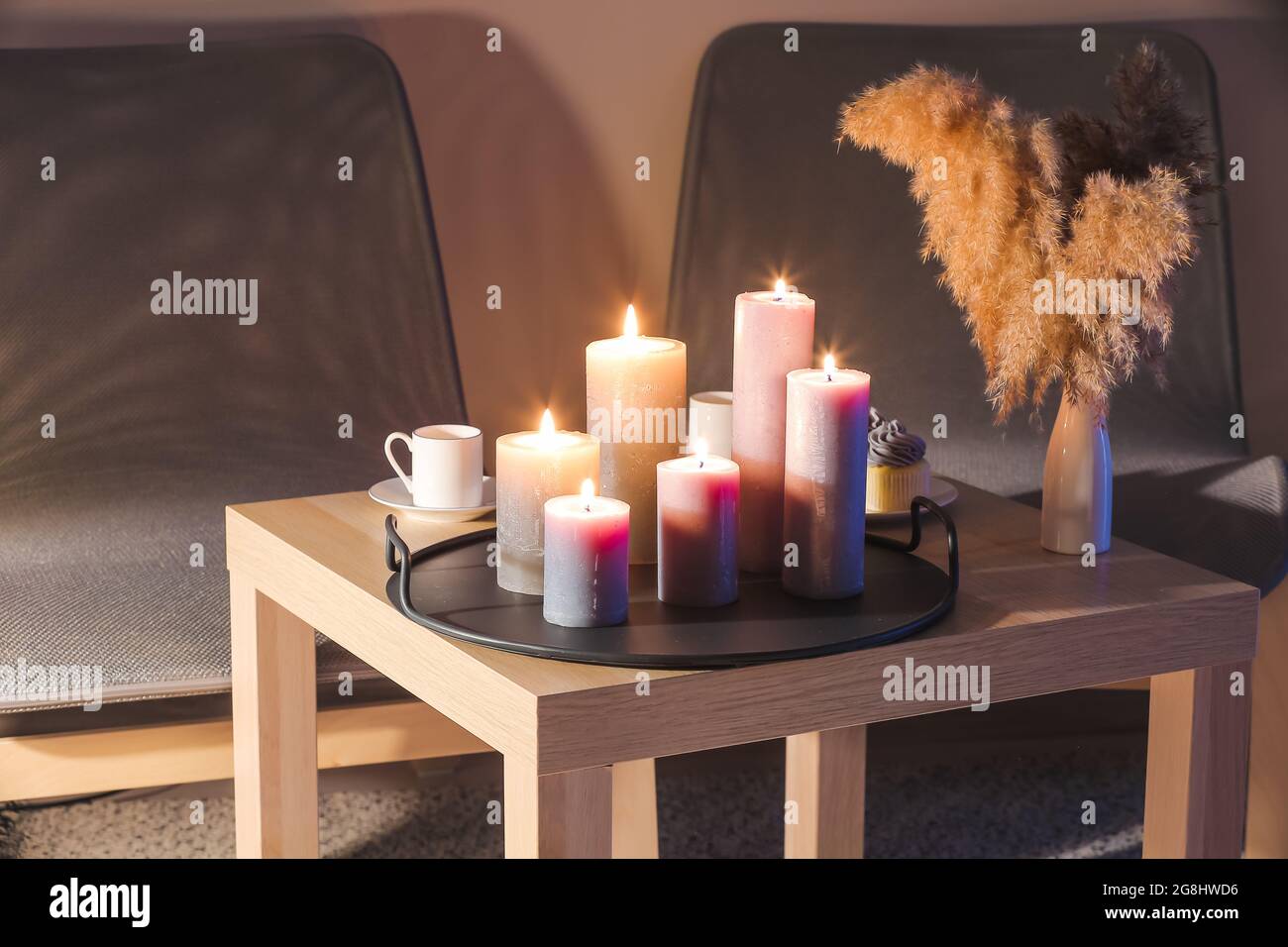 Burning candles on table in dark room Stock Photo - Alamy