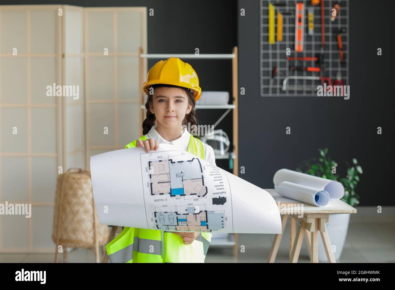 Cute little architect with house plan in office Stock Photo - Alamy
