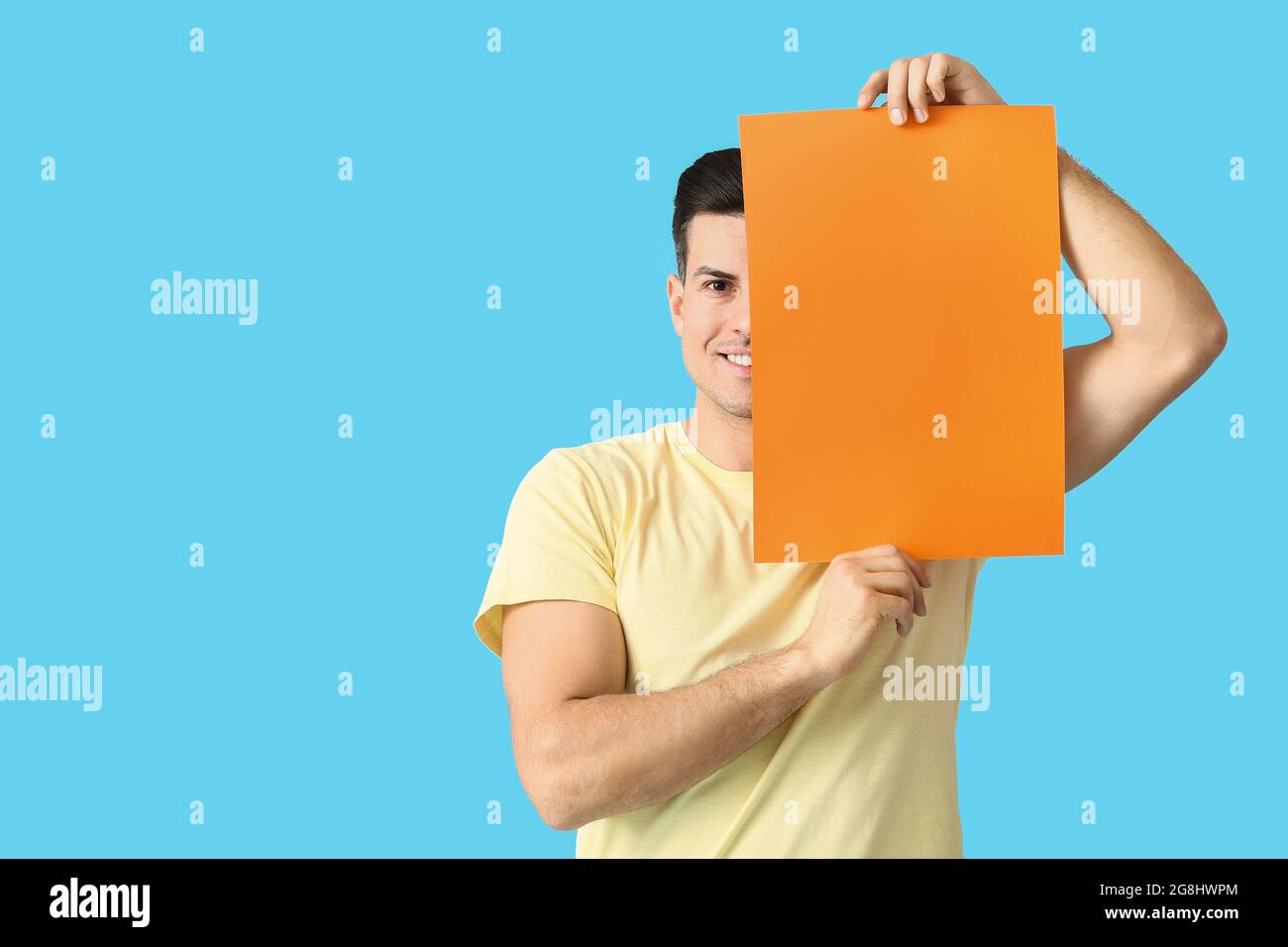 Young man with blank paper sheet on color background Stock Photo - Alamy