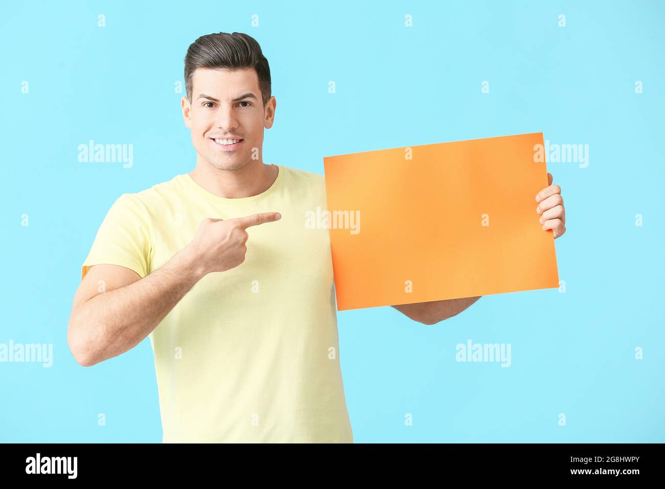 Young man with blank paper sheet on color background Stock Photo - Alamy