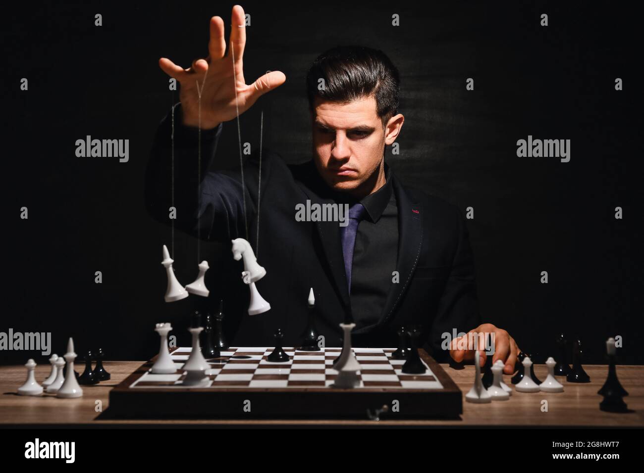 Man with strings and chess pieces at table on dark background Stock ...