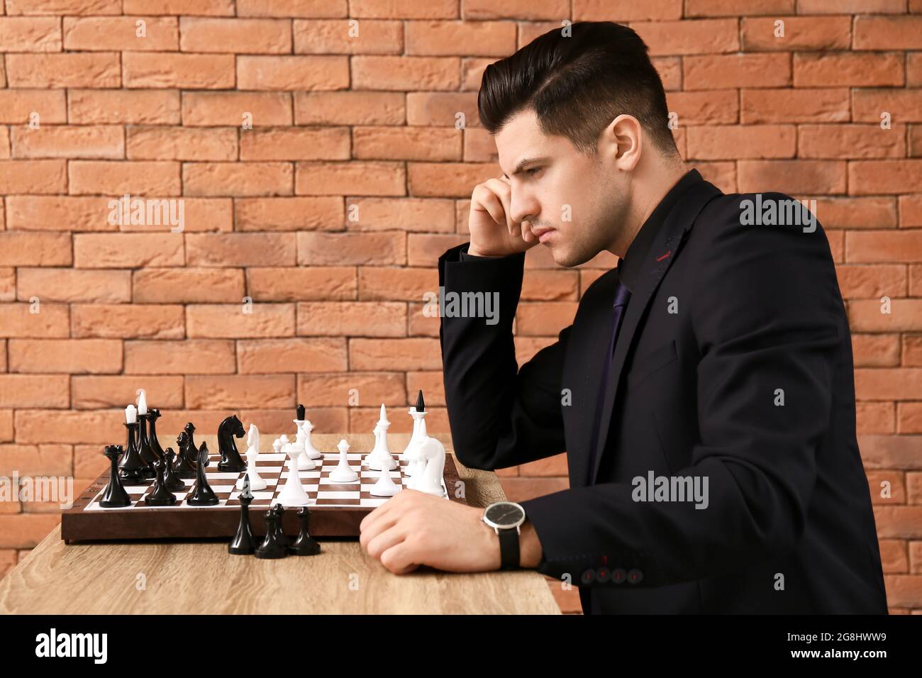 Thoughtful man playing chess on table near brick wall Stock Photo - Alamy