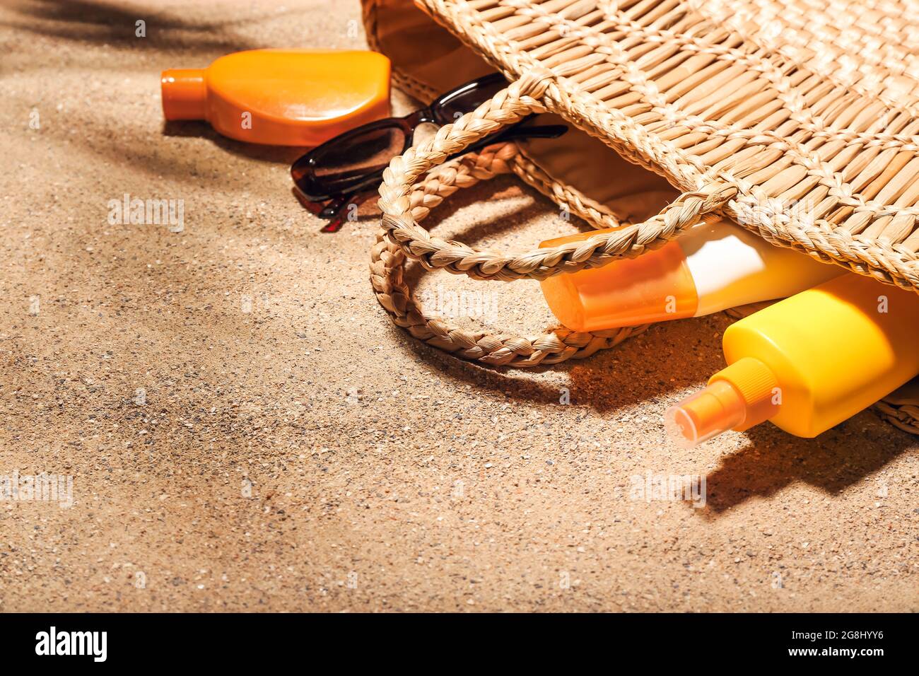 Bag with sunscreen cream and sunglasses on sand, closeup Stock Photo ...