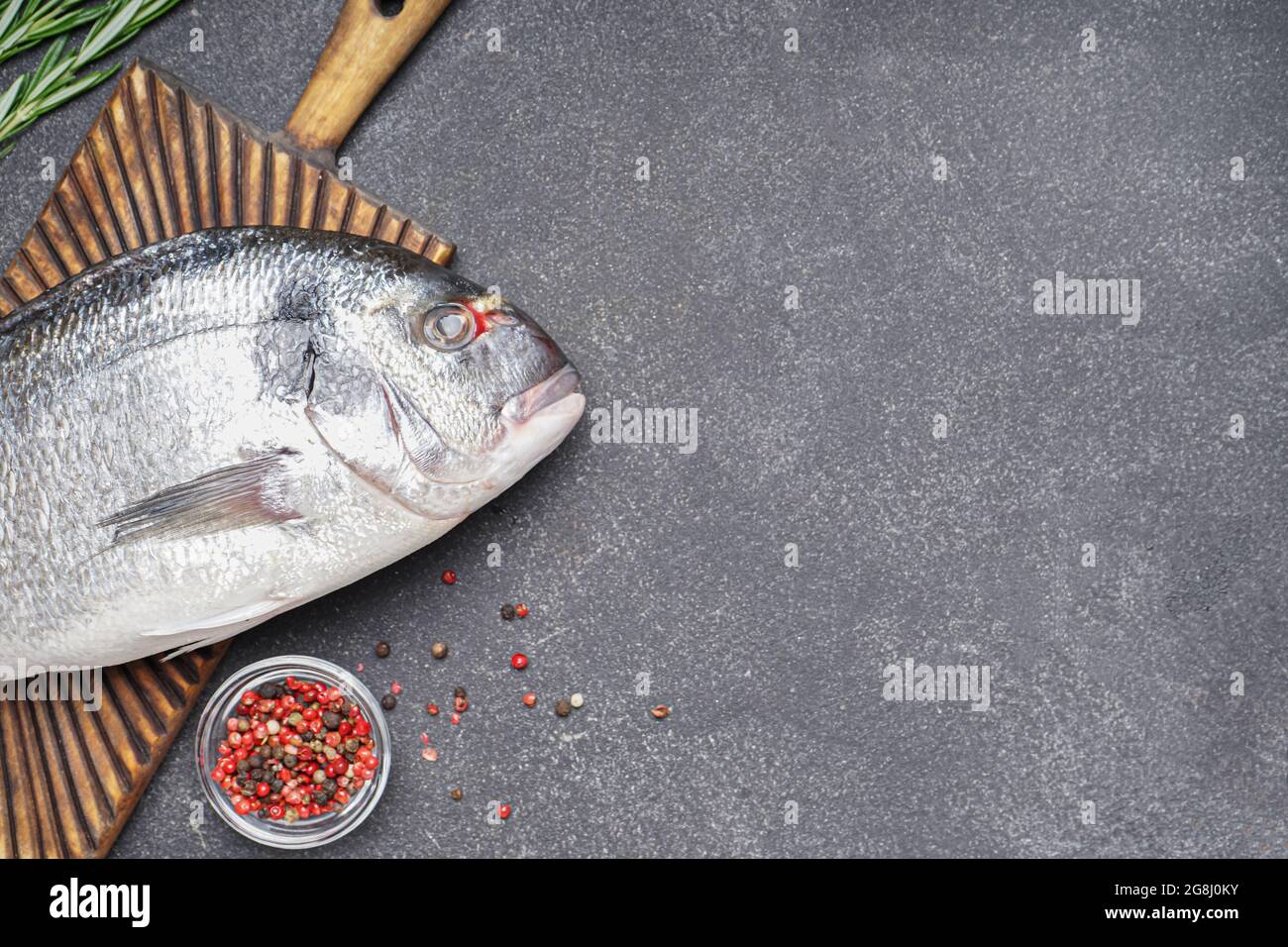 Board with raw dorado fish on dark background Stock Photo - Alamy
