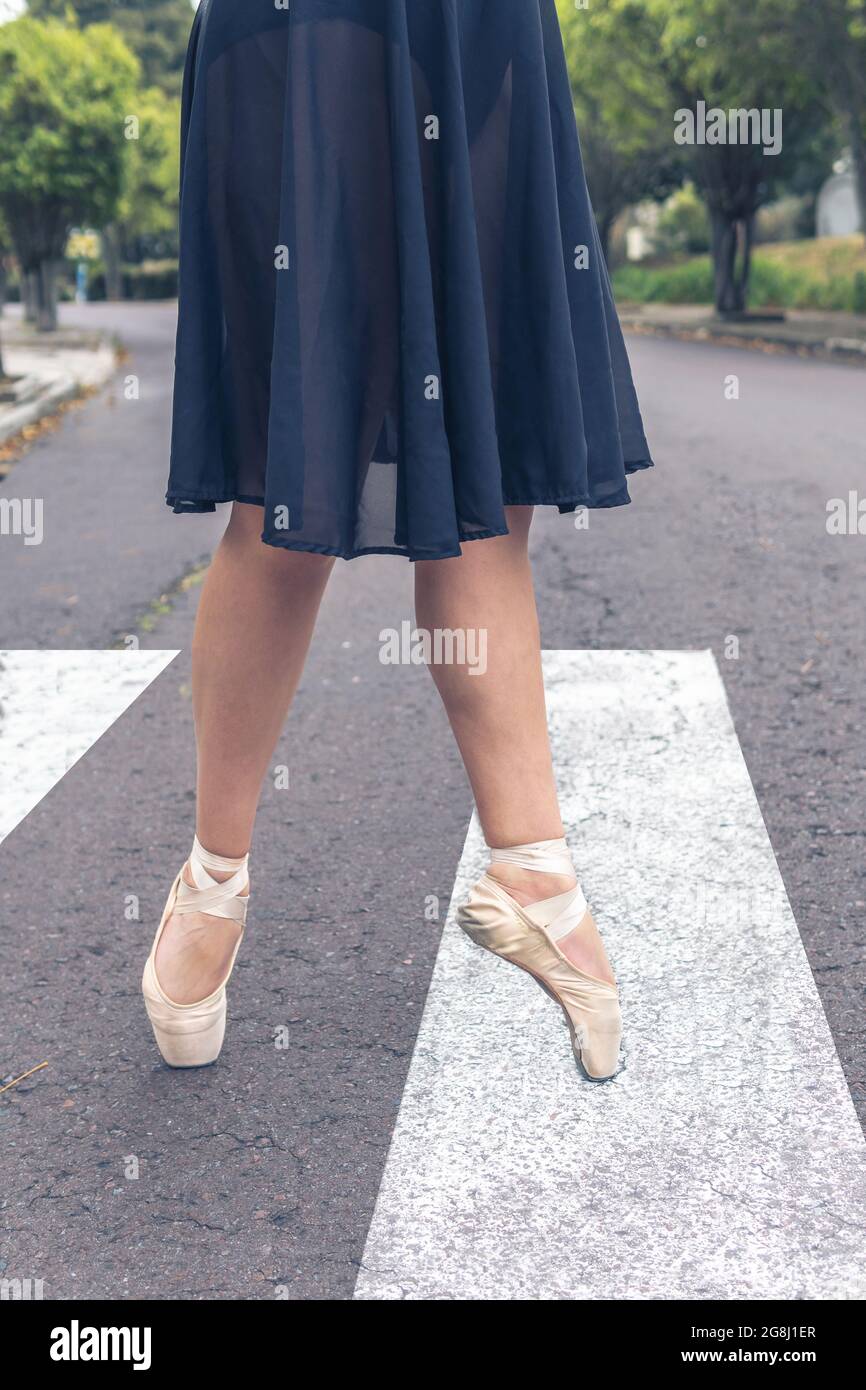 closeup of legs in pointe ballet shoes with black skirt on a pedestrian ...