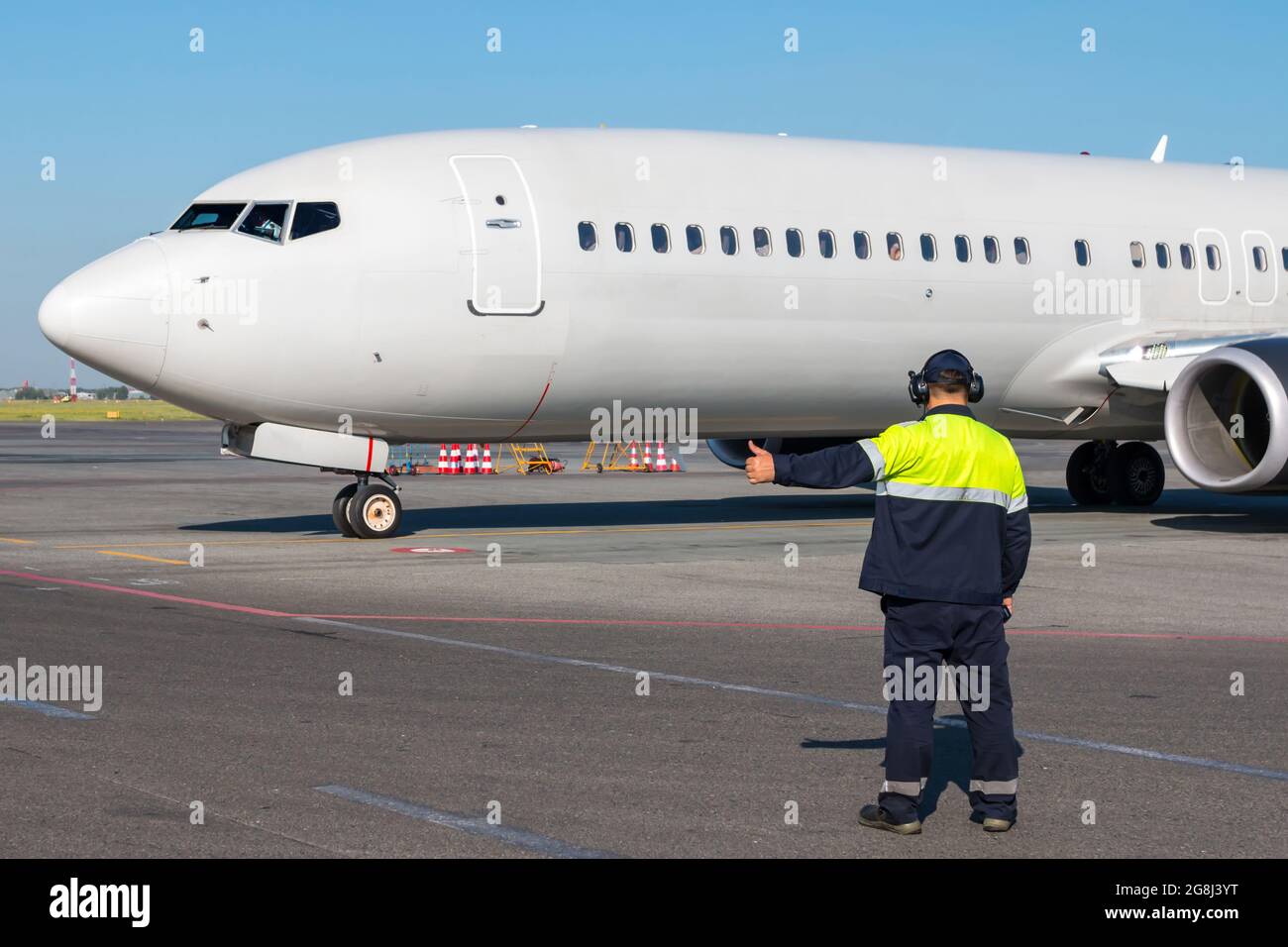 Aircraft marshaller showing take-off clearance sign to white passenger ...