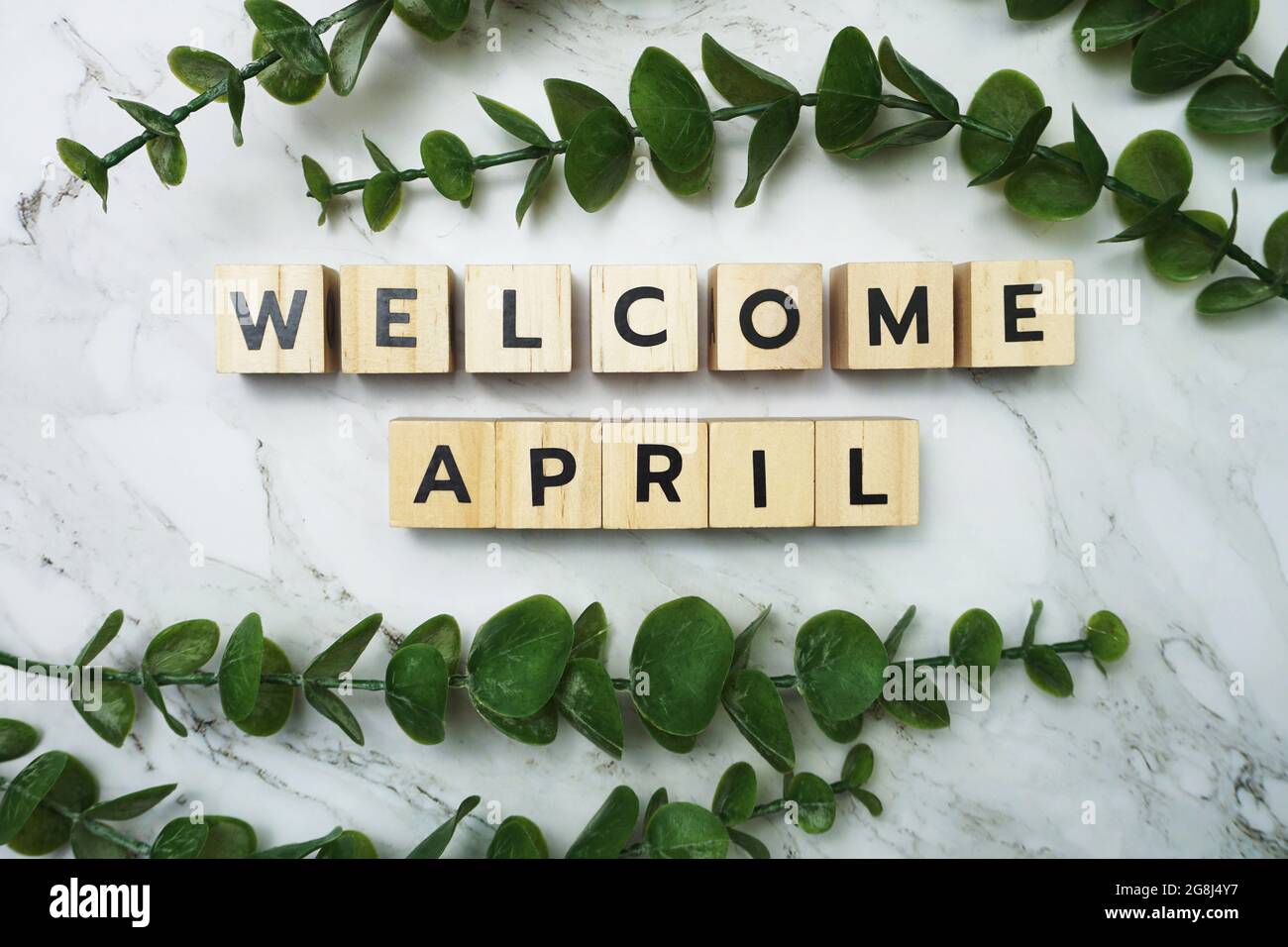 Welcome April alphabet letter with green leave flat lay on marble ...