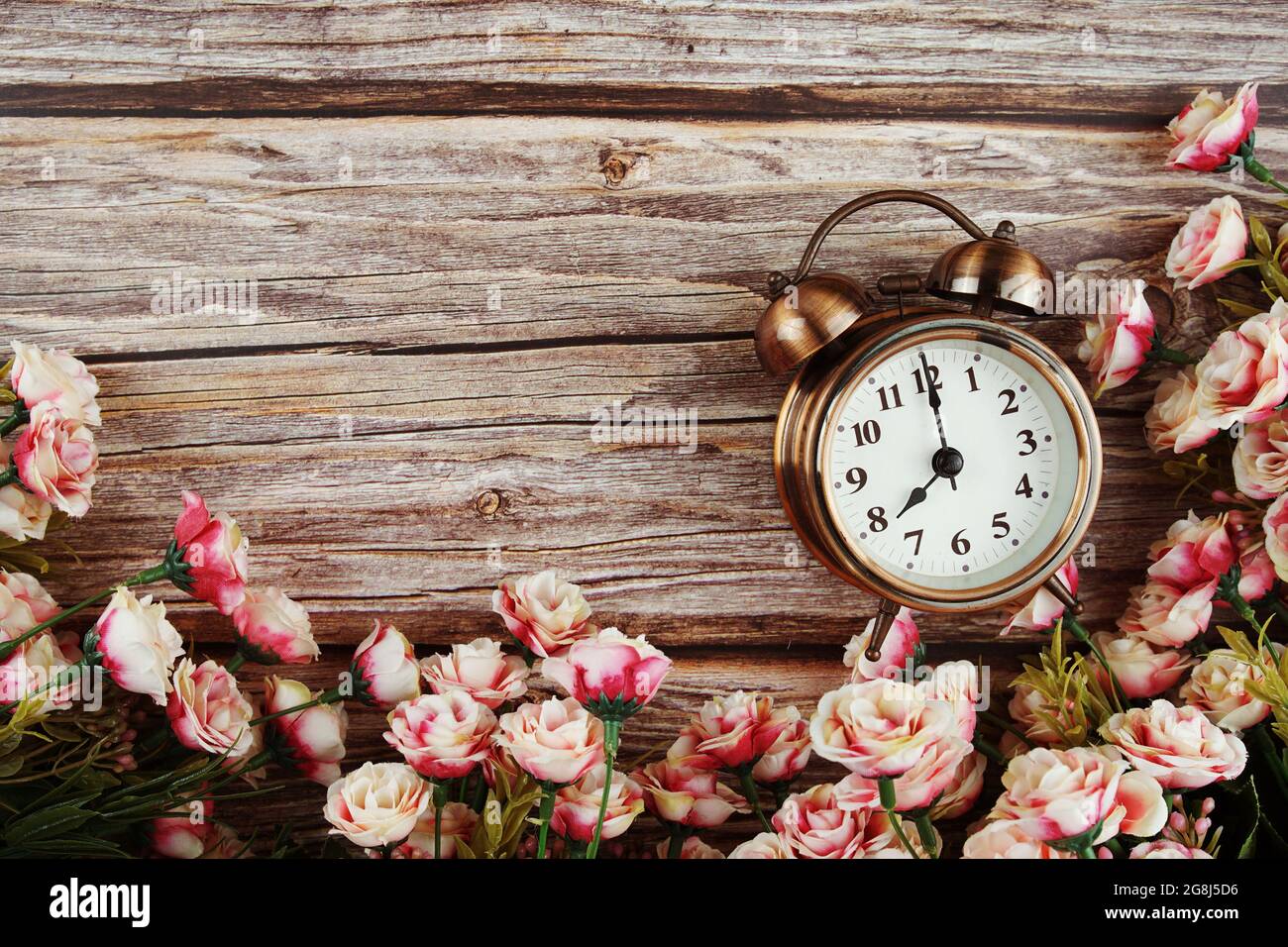 Alarm clock with Pink roses flowers border frame on wooden background ...