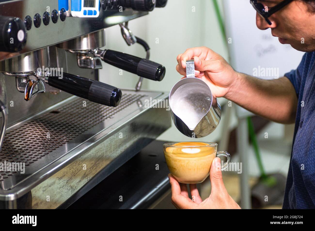 Hand of barista making latte or cappuccino coffee, pouring milk making ...