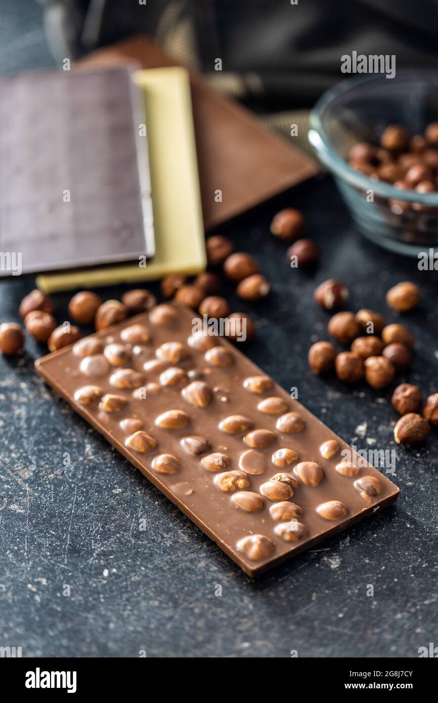 Chocolate bar with hazelnuts on black table Stock Photo - Alamy