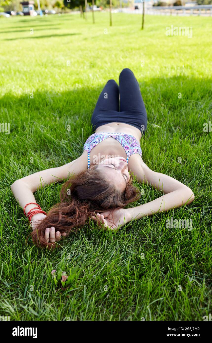 Portrait of a smiling girl lying on green grass. Woman relaxing ...