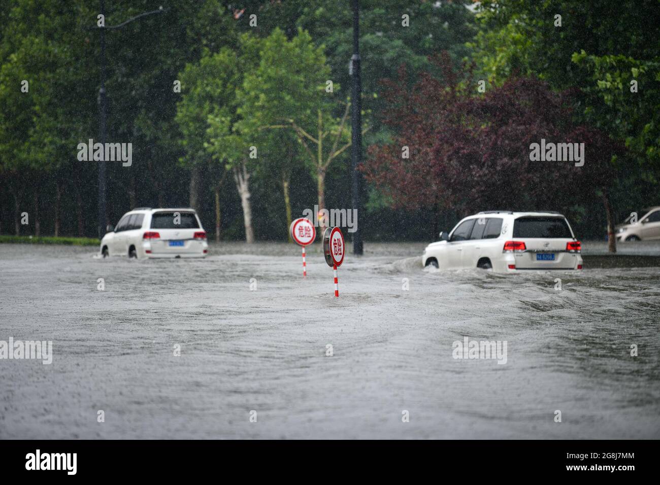 View of vehicles driving through city flood caused by continuous ...