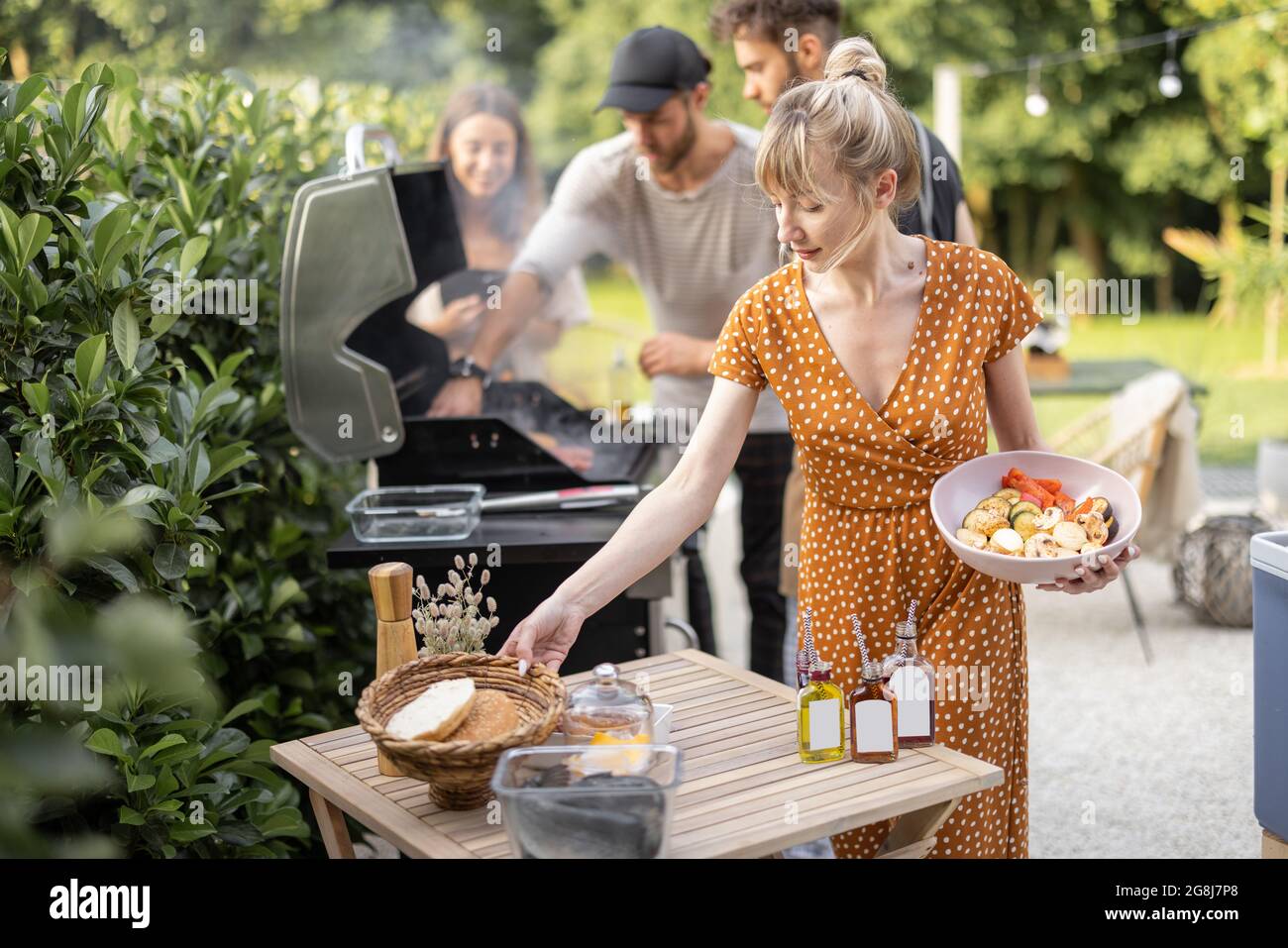Happe friends cooking on a grill at backyard Stock Photo - Alamy