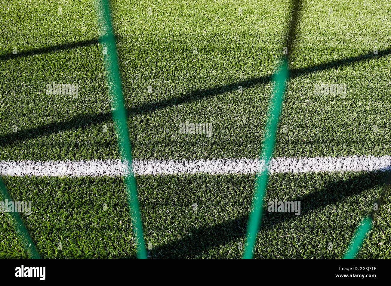 Lawn field for playing football behind the green fence mesh. Close-up ...