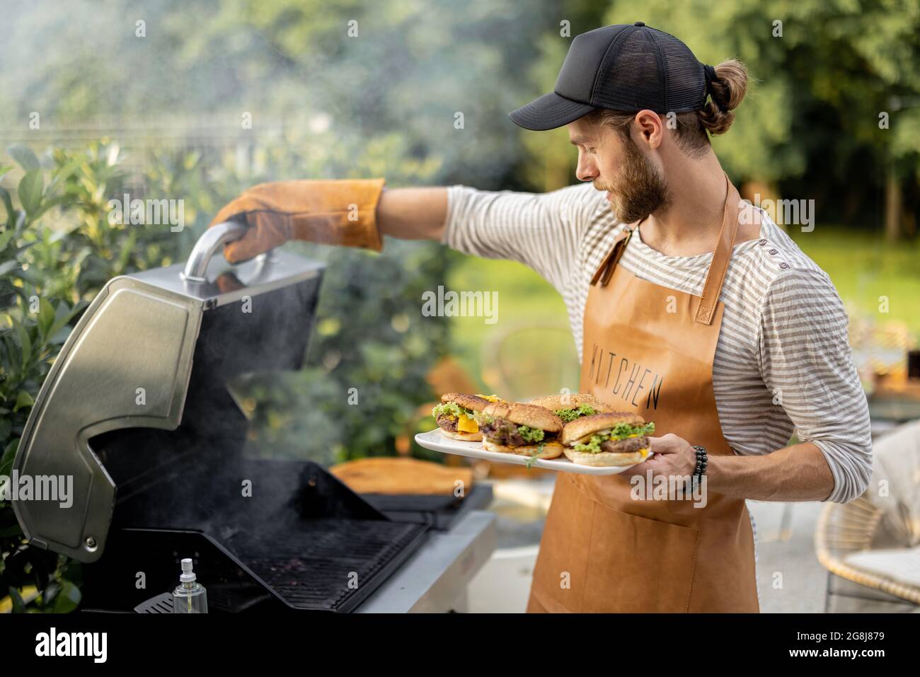 Man making burgers on a grill outdoors Stock Photo - Alamy