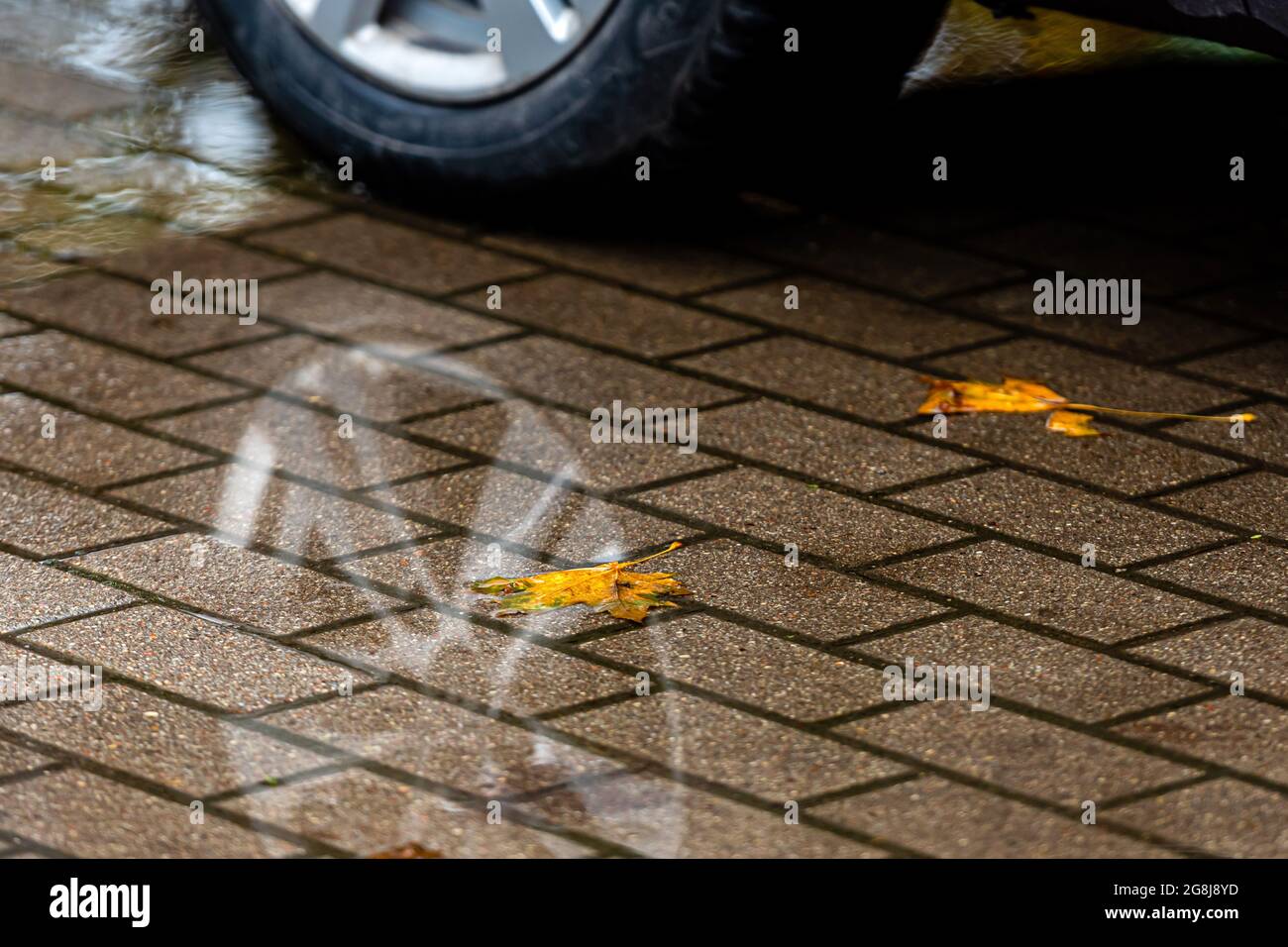 puddle on the pavement with a reflection of the car wheel and colorful ...