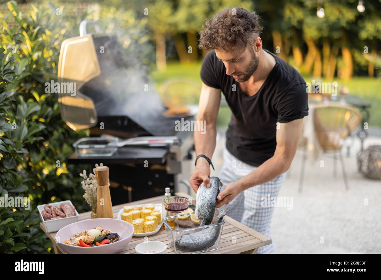Man cooking fish and vegetables on a grill outdoors Stock Photo - Alamy